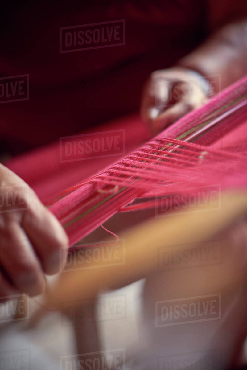 Hispanic woman weaving fabric on loom - Stock Photo - Dissolve