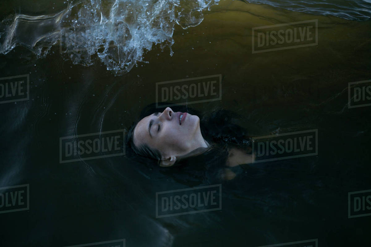 Caucasian woman floating in ocean with eyes closed - Stock Photo - Dissolve