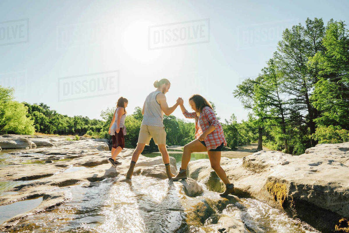 Man helping woman crossing river - Royalty-free Stock Photo | Dissolve