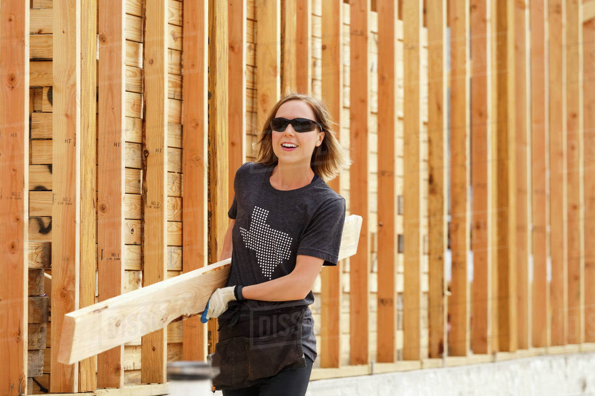 Caucasian woman carrying lumber at construction site - Royalty-free ...