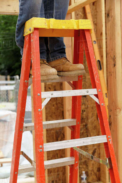Legs of Caucasian man standing on ladder at construction site - Royalty ...