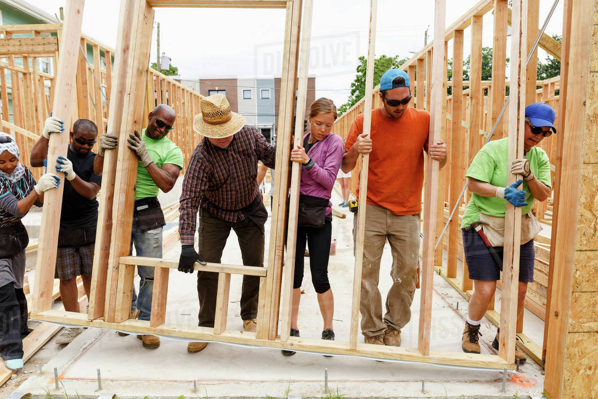 Volunteers lifting wall at construction site - Royalty-free Stock Photo ...