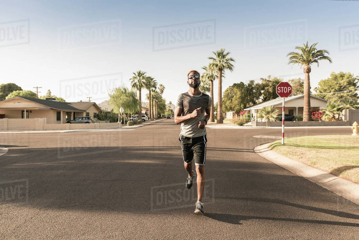 Black man running on street in neighborhood - Stock Photo - Dissolve