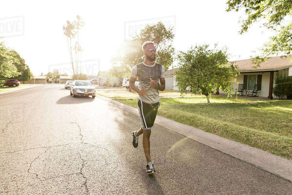 Black man running on street in neighborhood - Stock Photo - Dissolve