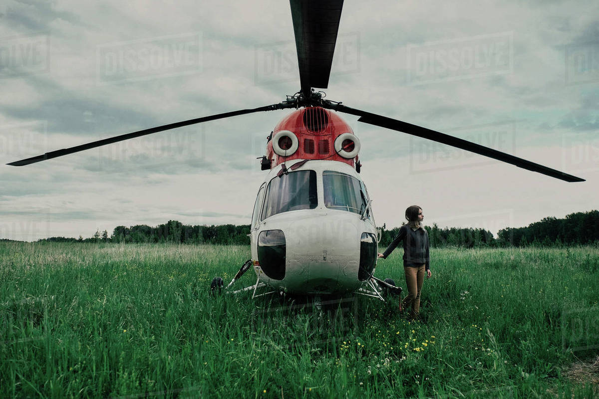 Caucasian woman standing near helicopter in field - Stock Photo - Dissolve