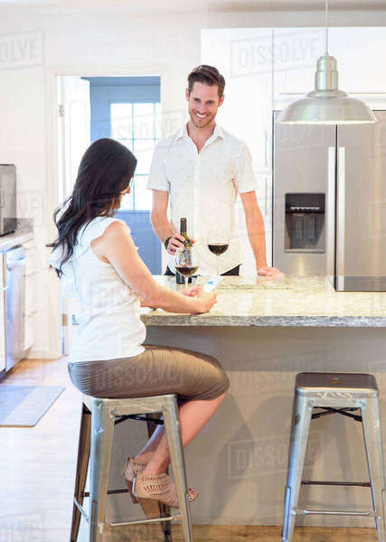 Smiling Caucasian couple drinking red wine in kitchen - Stock Photo ...