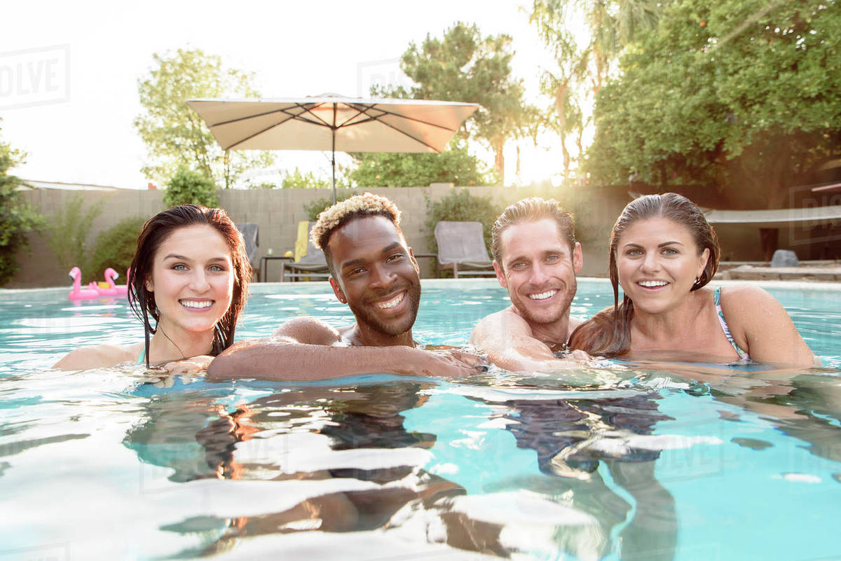 Portrait of smiling friends in swimming pool - Stock Photo - Dissolve