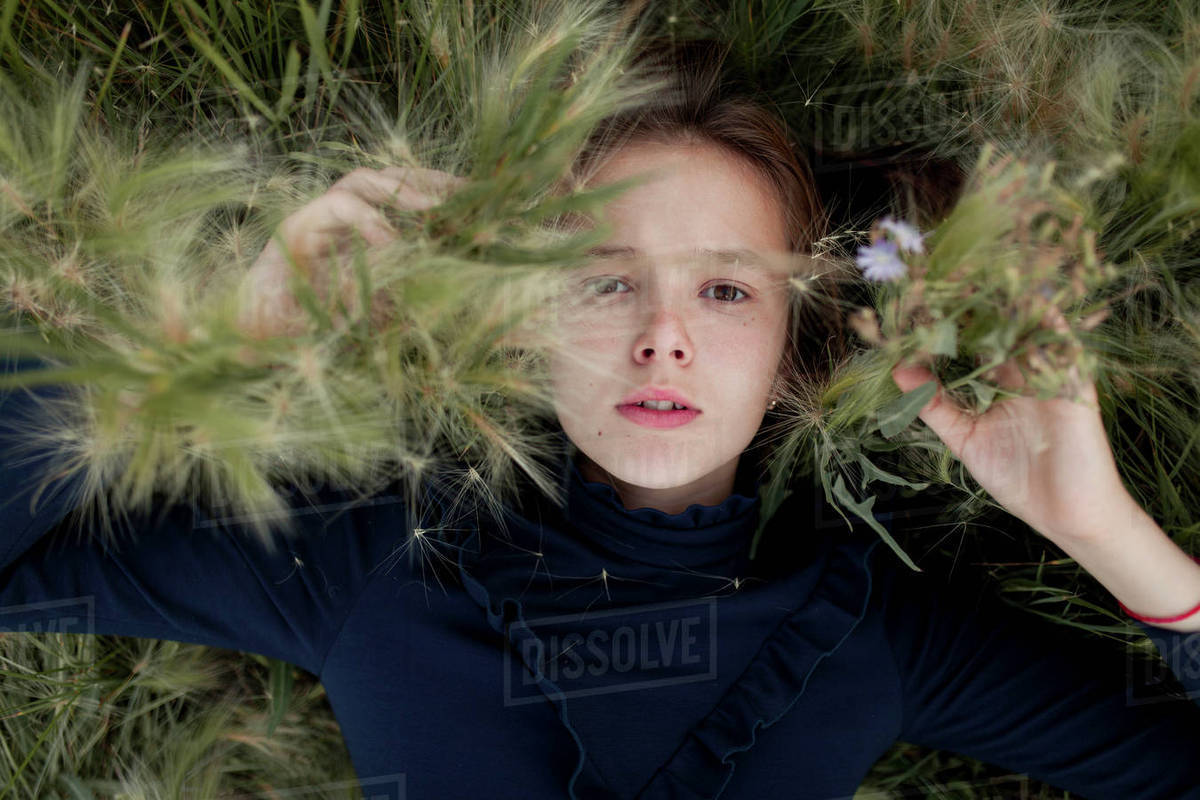 Serious Caucasian girl laying in field - Royalty-free Stock Photo ...
