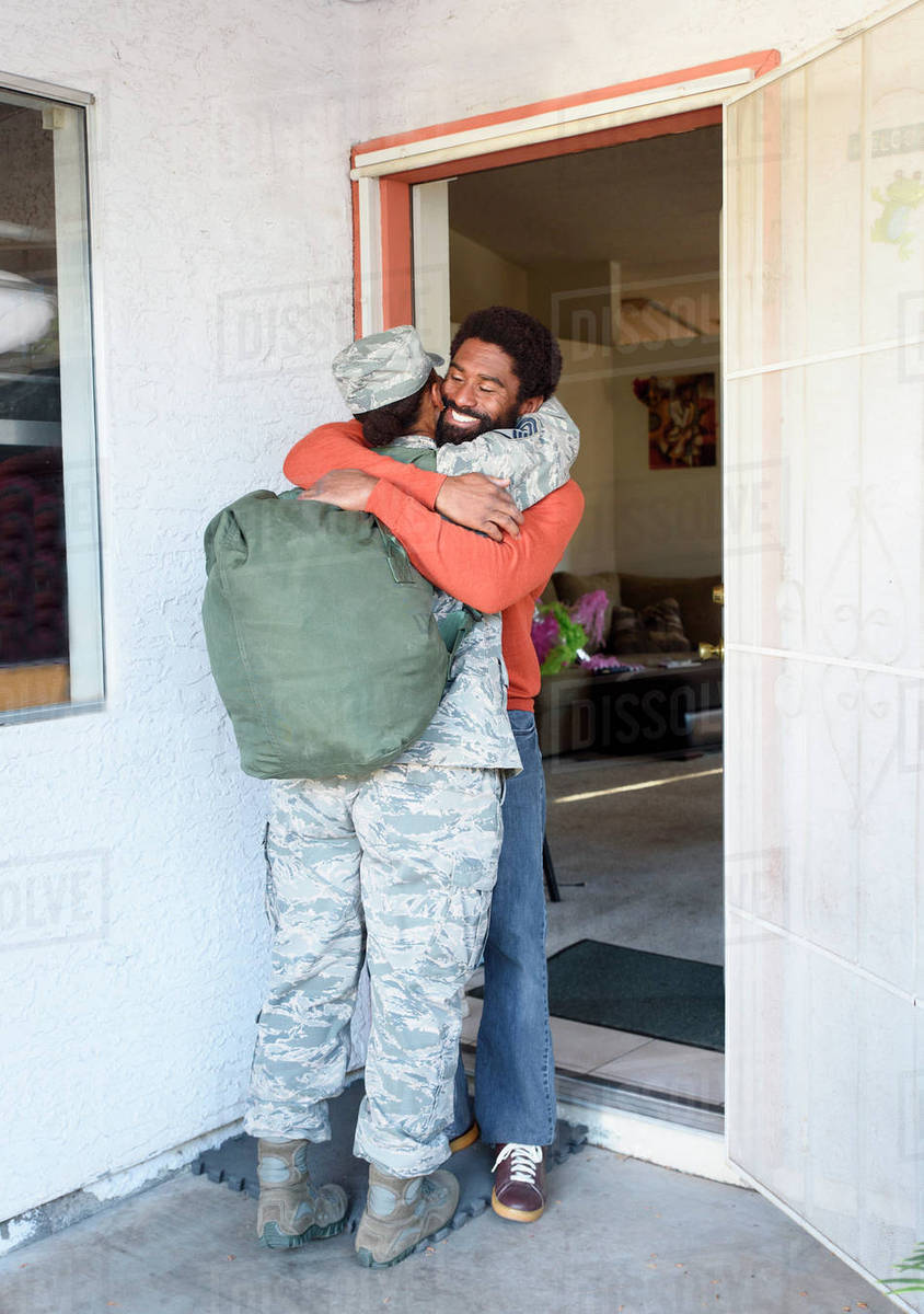 Black woman soldier hugging man in doorway - Stock Photo - Dissolve