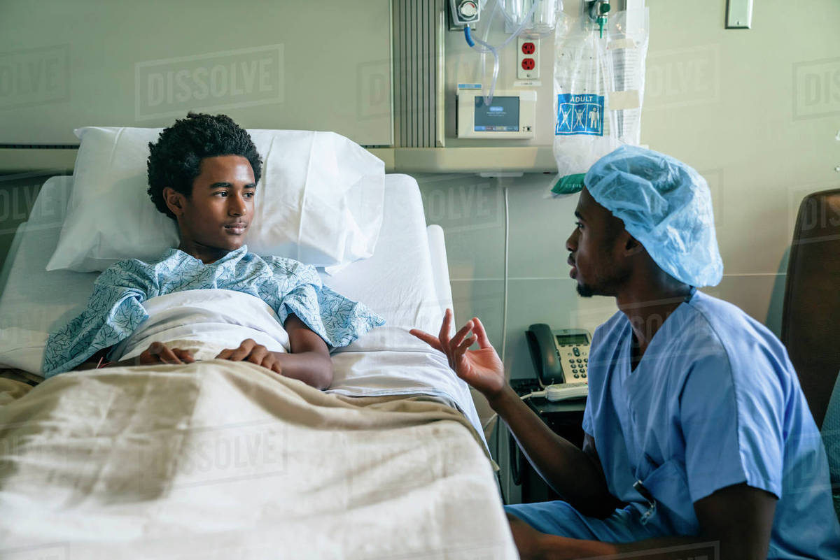Black nurse talking to boy in hospital bed - Royalty-free Stock Photo ...