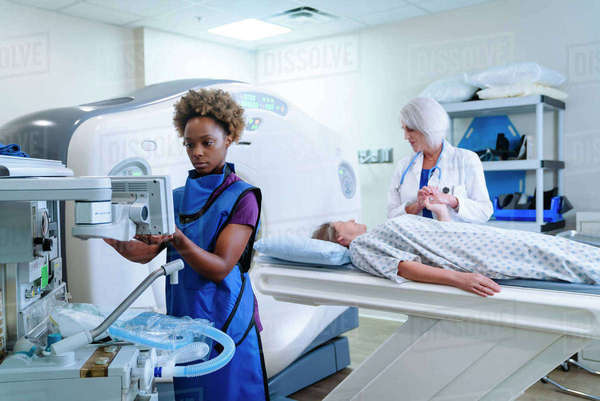 Technician preparing scanner for doctor comforting patient - Stock ...