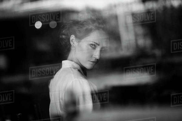 Portrait of serious Caucasian woman behind window - Stock Photo - Dissolve