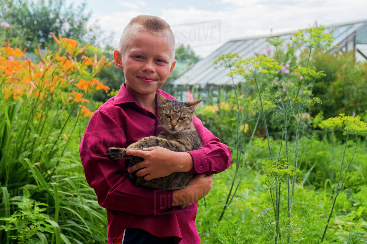 Caucasian boy holding cat on farm - Royalty-free Stock Photo | Dissolve