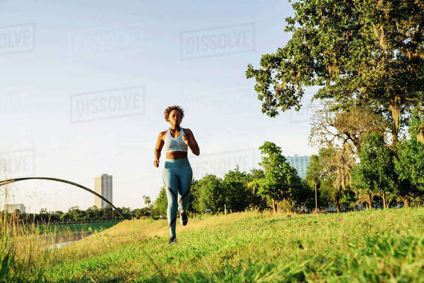 Mixed Race woman running in grass near waterfront - Royalty-free Stock ...