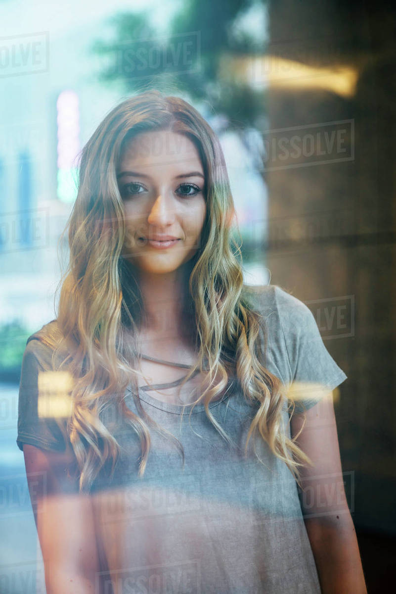 Portrait of serious Caucasian woman behind window - Stock Photo - Dissolve