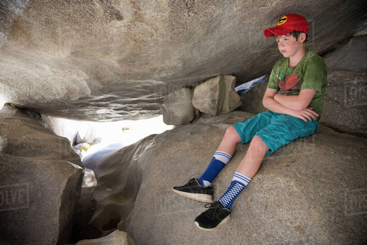 Pensive Caucasian boy sitting on rocks - Royalty-free Stock Photo ...