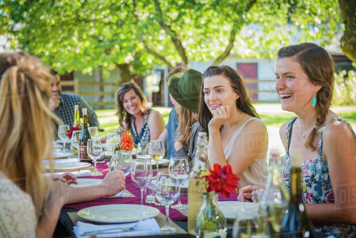 Caucasian women talking at table at party outdoors - Stock Photo - Dissolve