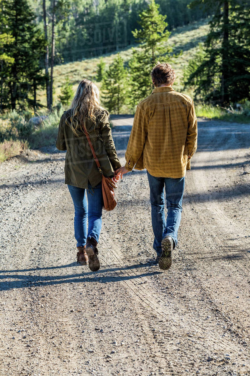 Caucasian couple walking on dirt road holding hands - Stock Photo ...