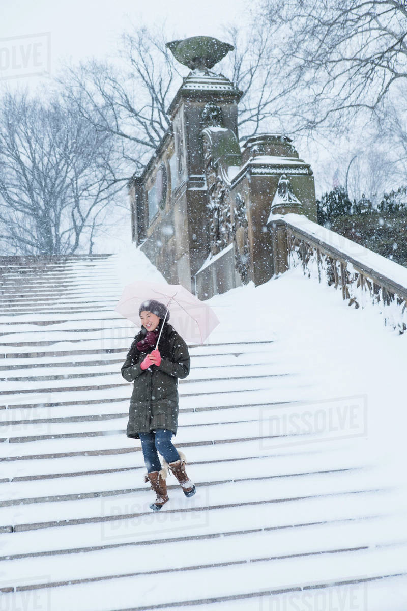 Asian woman walking on snowy steps - Stock Photo - Dissolve