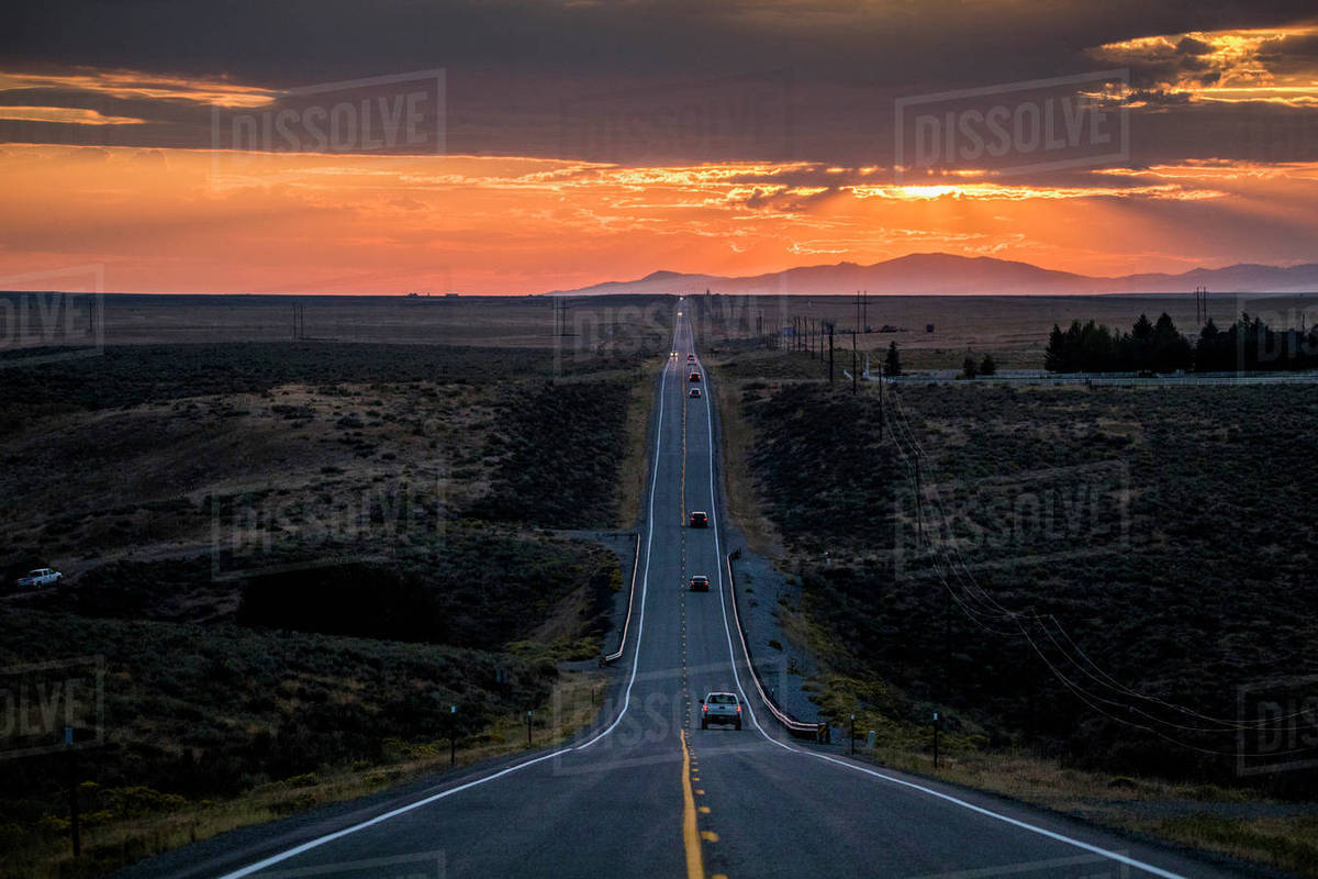 Cars driving on remote road at sunset - Royalty-free Stock Photo | Dissolve