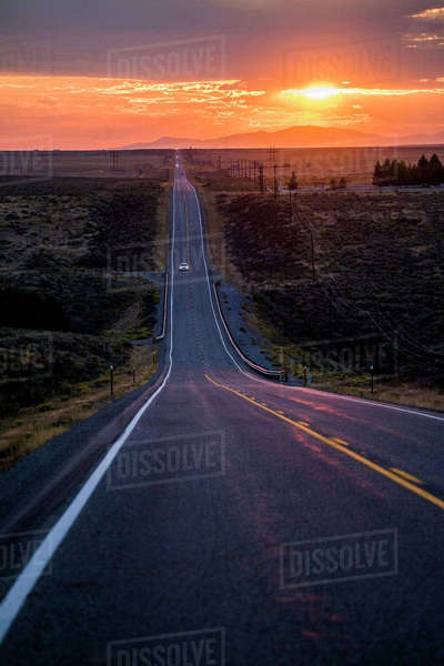 Cars driving on remote road at sunset - Royalty-free Stock Photo | Dissolve