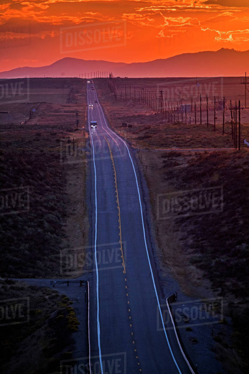 Cars driving on remote road at sunset - Stock Photo - Dissolve