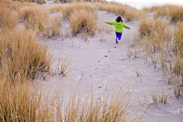 Caucasian girl running on sand dunes - Royalty-free Stock Photo | Dissolve