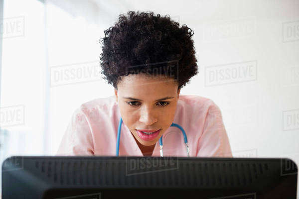Black nurse working on computer in office - Stock Photo - Dissolve