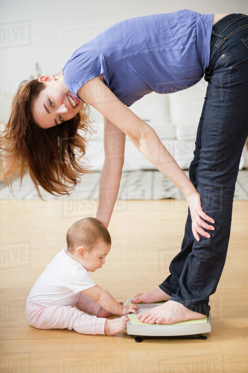 Mother with new baby standing on scale - Stock Photo - Dissolve