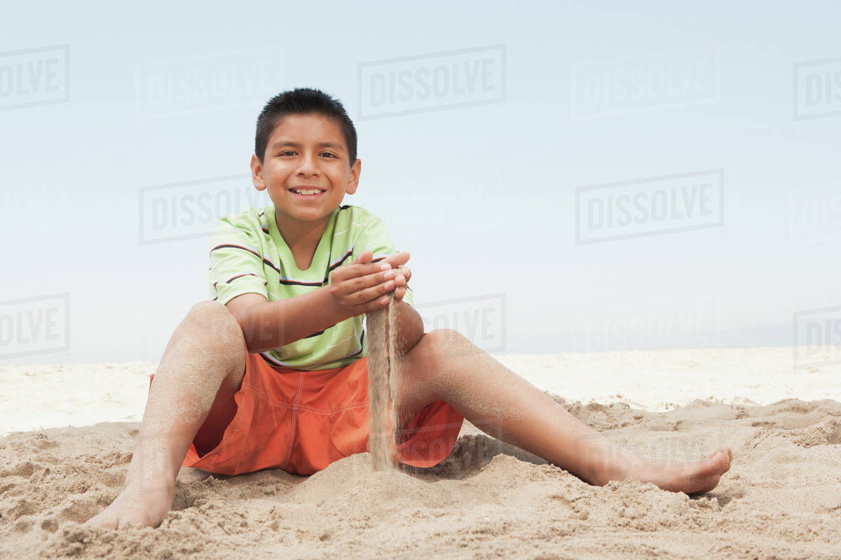 Hispanic boy playing in sand on beach - Royalty-free Stock Photo | Dissolve