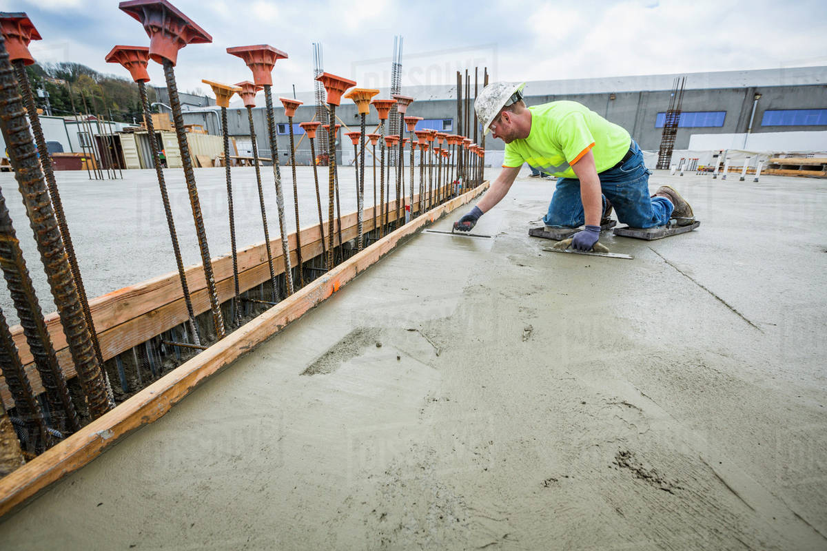 Worker finishing concrete at construction site - Stock Photo - Dissolve