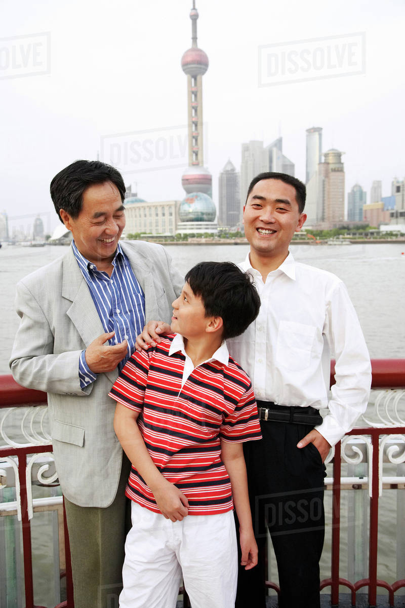 Three generations of men smiling by city skyline, Shanghai, China ...