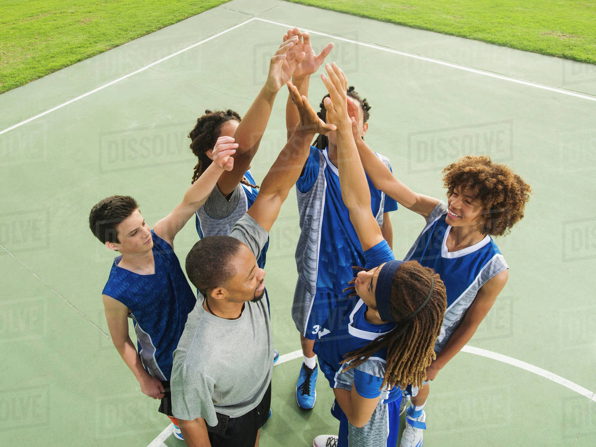 Basketball team high fiving on court - Stock Photo - Dissolve