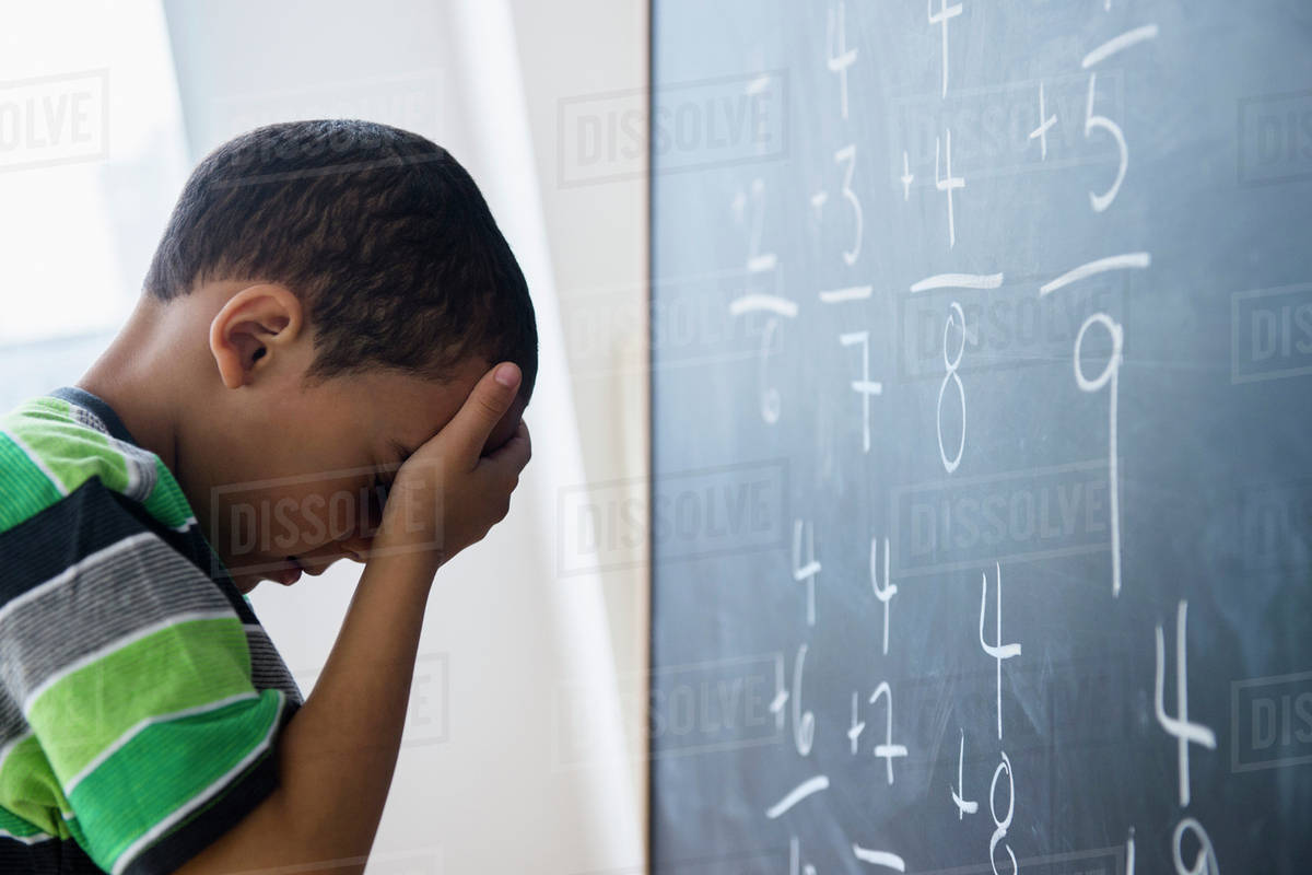 Mixed race boy doing math problems at board in class - Stock Photo ...
