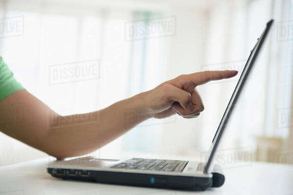 Mixed race man pointing to laptop screen - Stock Photo - Dissolve