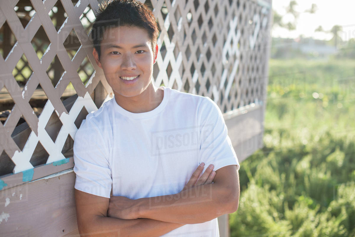Korean man leaning against porch outdoors - Stock Photo - Dissolve