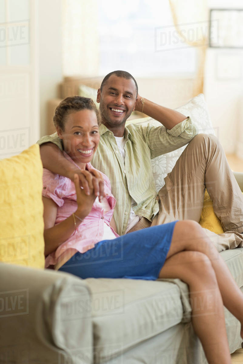 Couple smiling on sofa in living room - Royalty-free Stock Photo | Dissolve