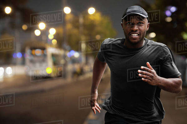 Black man running on city street at night - Stock Photo - Dissolve