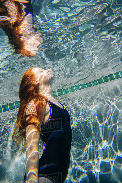 Teenage girl with red hair swimming underwater in pool - Royalty-free ...