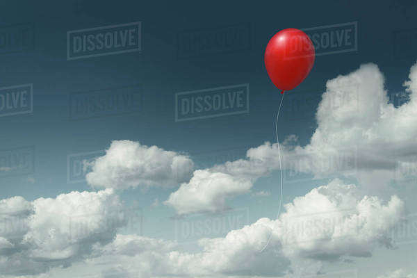 Red balloon floating in cloudy sky - Stock Photo - Dissolve