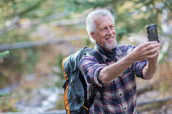 Caucasian hiker taking cell phone photograph in forest - Royalty-free ...