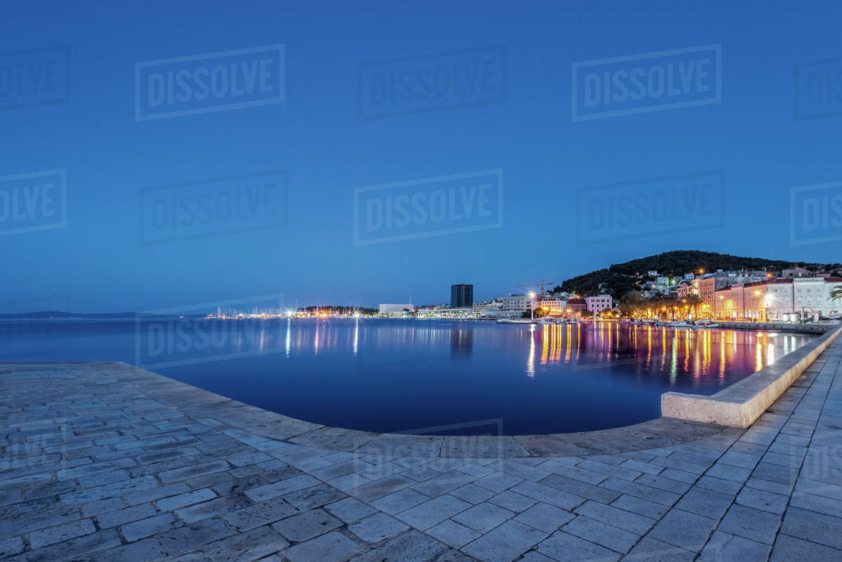 Waterfront sidewalk, illuminated boats and dock at dusk, Split, Split ...
