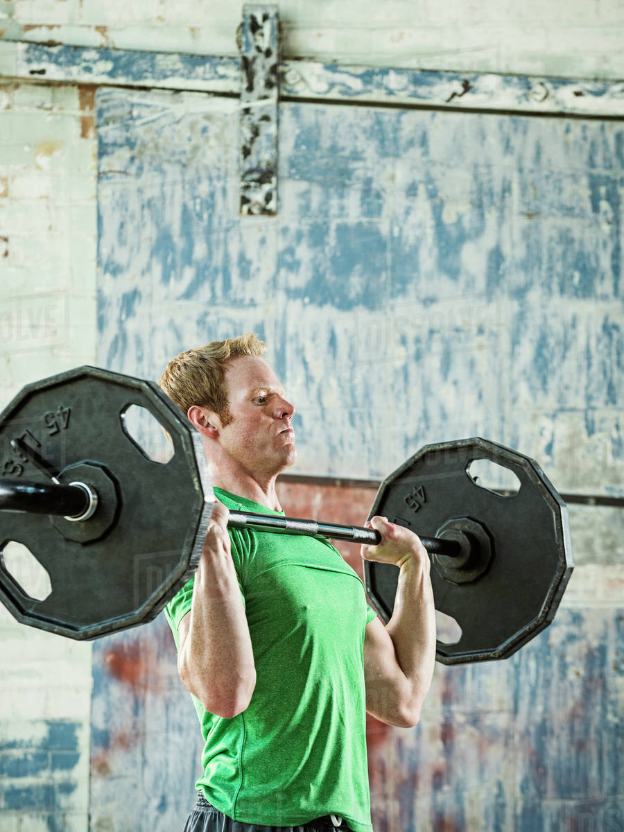 Caucasian man lifting weights in warehouse - Royalty-free Stock Photo ...