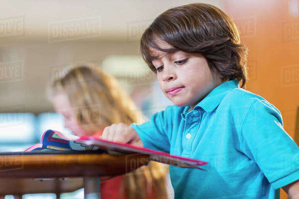 Student reading book at desk - Royalty-free Stock Photo | Dissolve