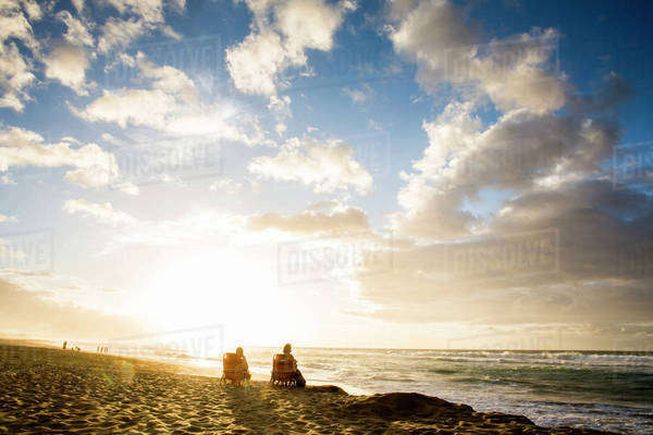 People relaxing on beach at sunrise - Stock Photo - Dissolve