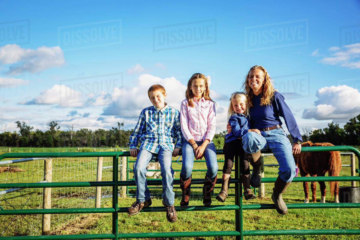 Caucasian farmer and children sitting on fence on ranch - Royalty-free ...
