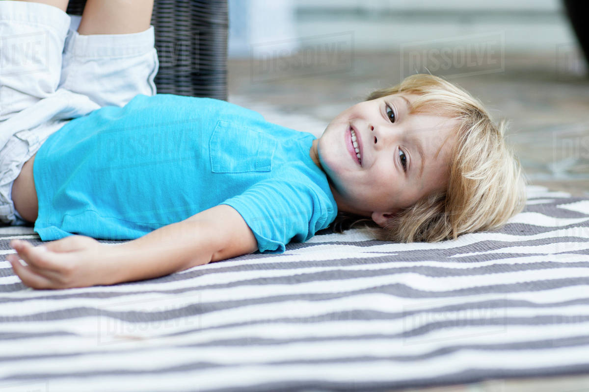 Smiling Caucasian boy laying on rug - Royalty-free Stock Photo | Dissolve