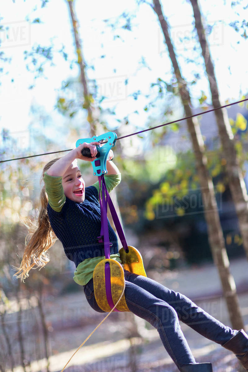 Caucasian girl zip lining in forest - Royalty-free Stock Photo | Dissolve