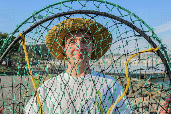 Caucasian man holding fishing net - Royalty-free Stock Photo | Dissolve
