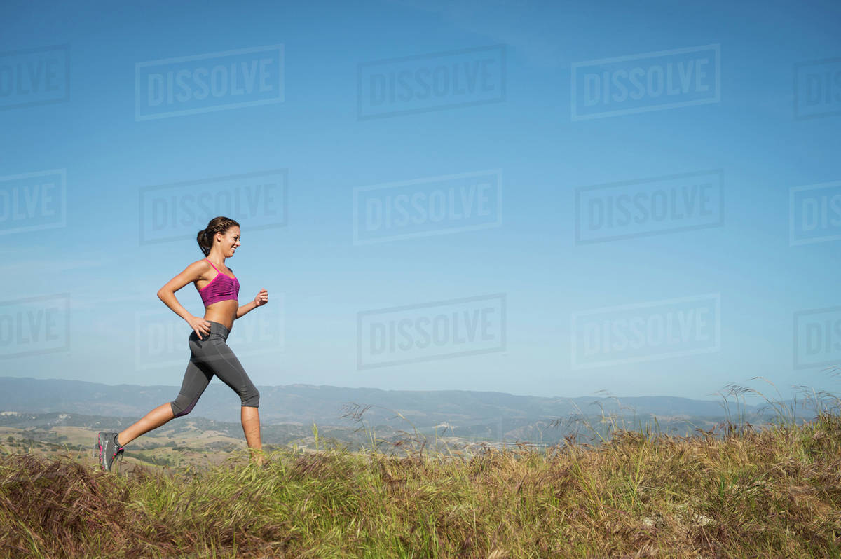 Mixed race woman running in rural landscape - Stock Photo - Dissolve